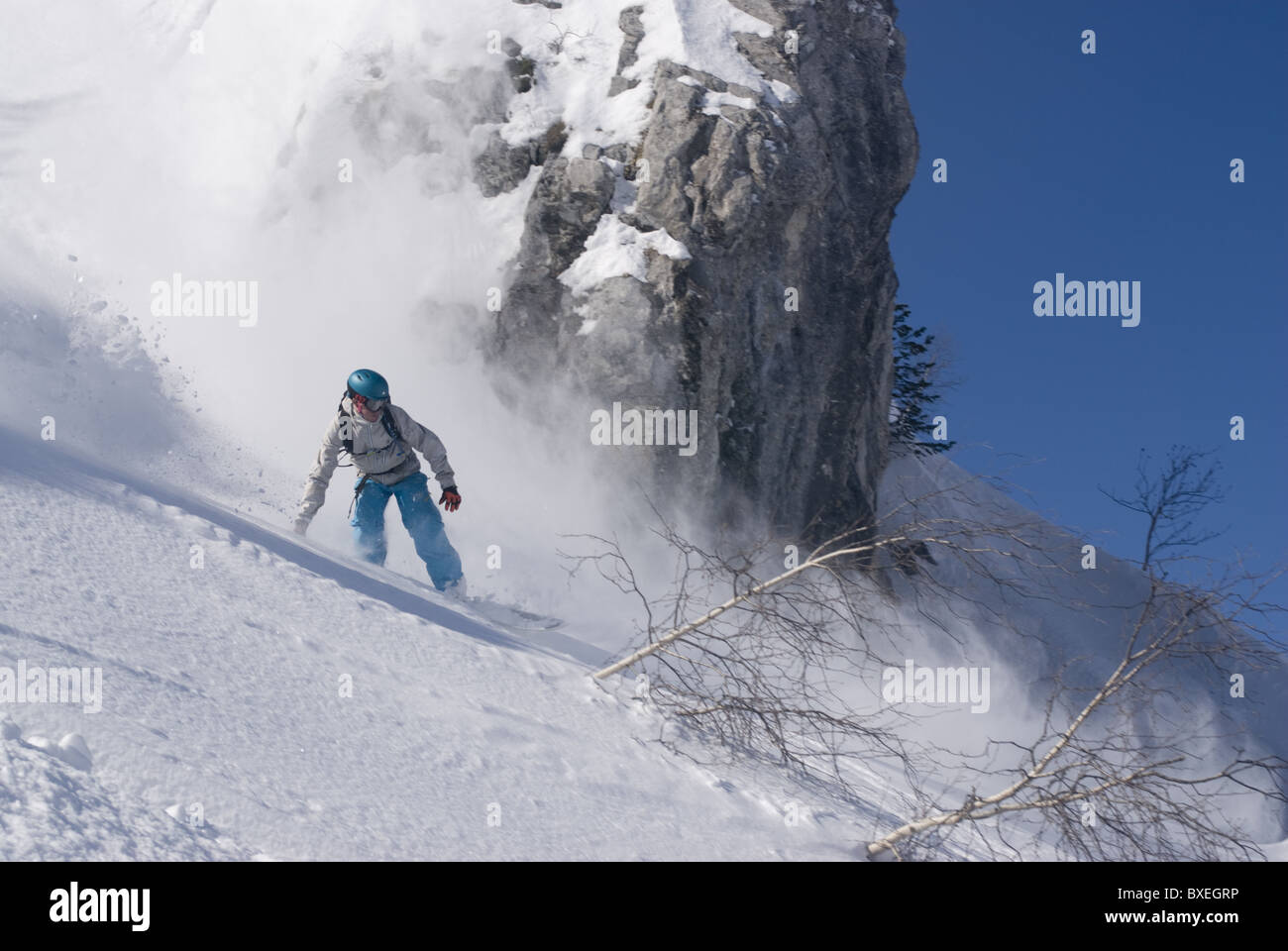 A snowboarder making a turn in deep powder snow, with trees in the ...