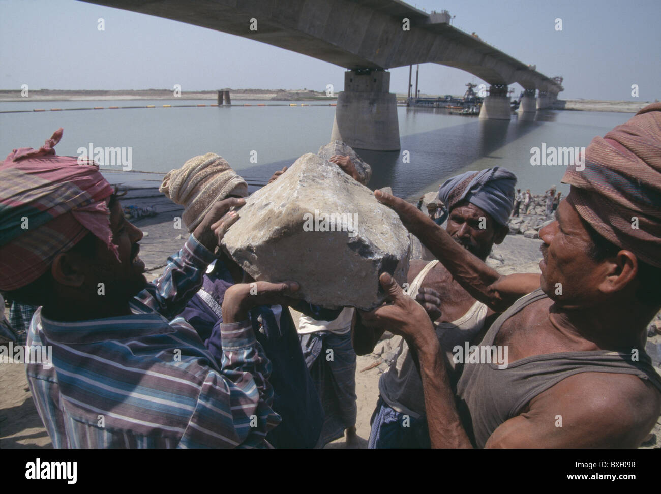Workers move stone blocks to reinforce a shoreline of the World Bank ...