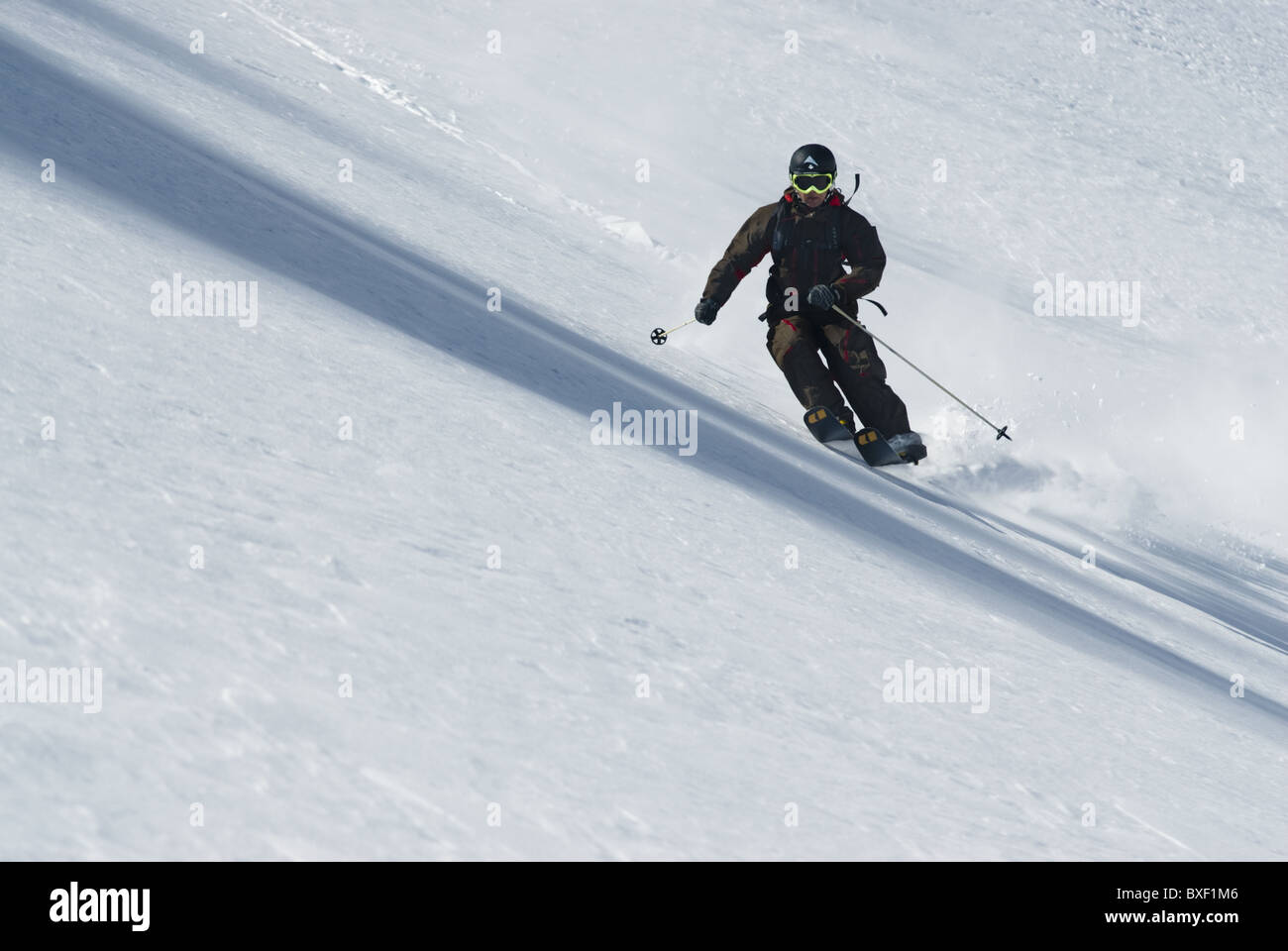 A free skier, skiing towards the camera, making fast turns on hard ...