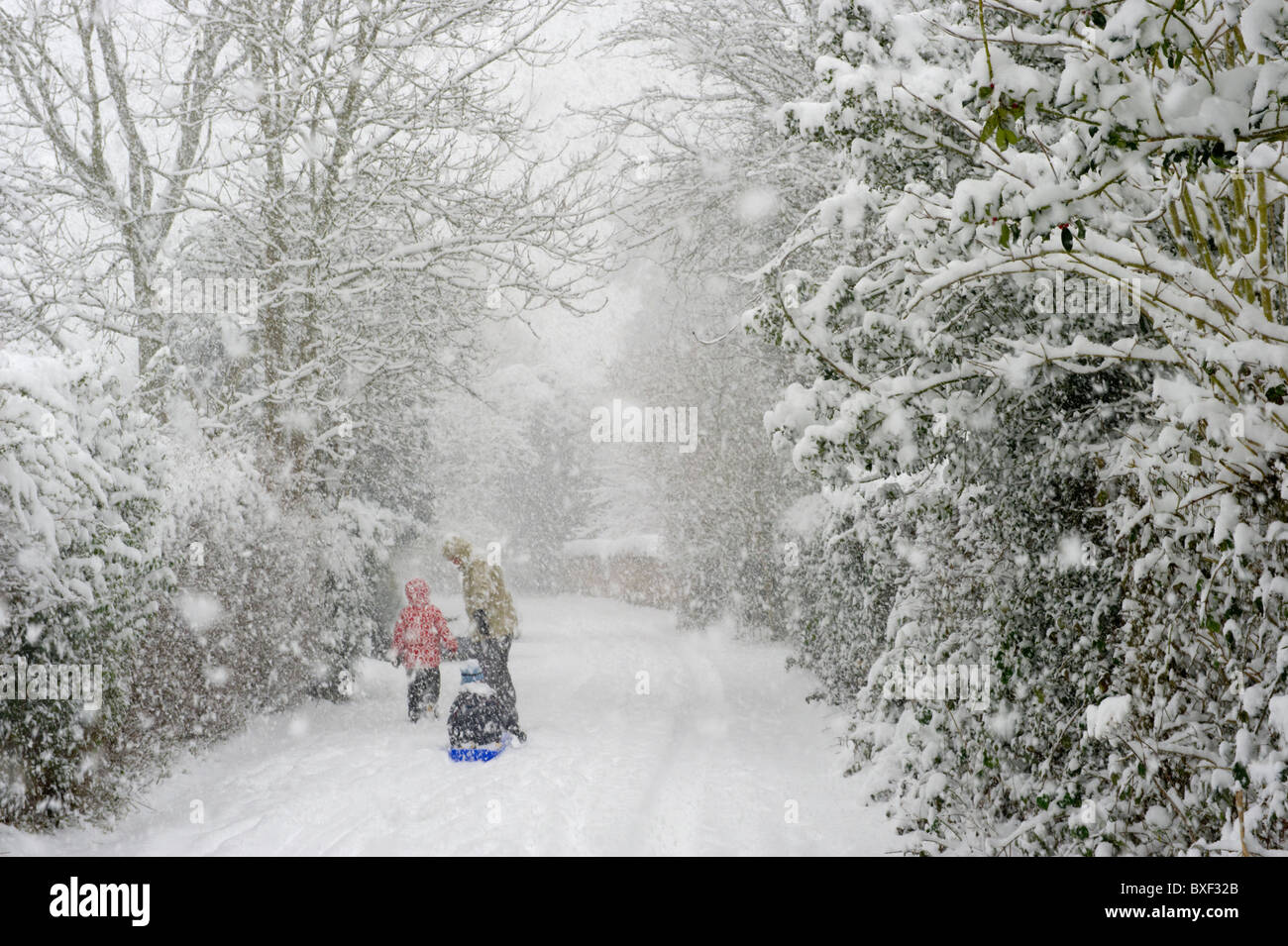 A father and his child with a toboggan in heavy snowfall blizzard ...