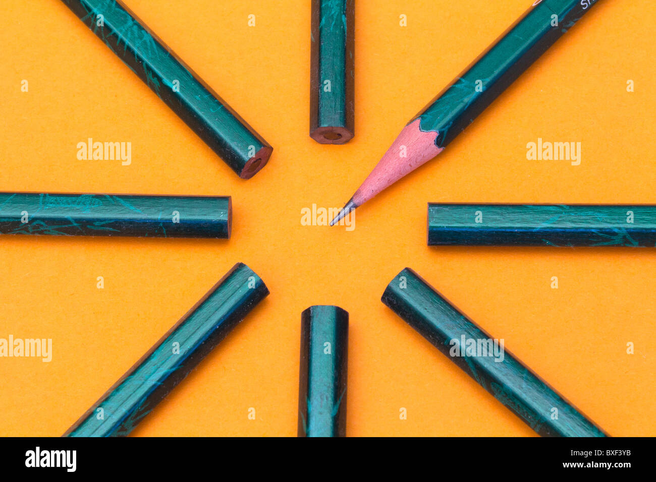 seven broken pencils and one pointed pencil on an orange background ...