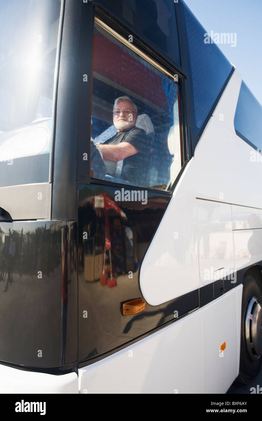 Elderly tour bus driver at wheel, view through window Stock Photo - Alamy