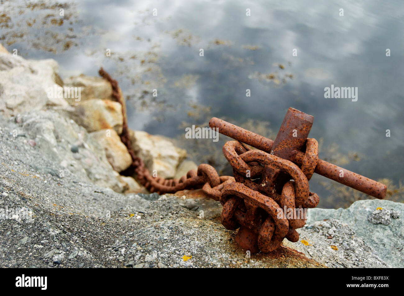 A rusty chain hanging from a rock Stock Photo - Alamy