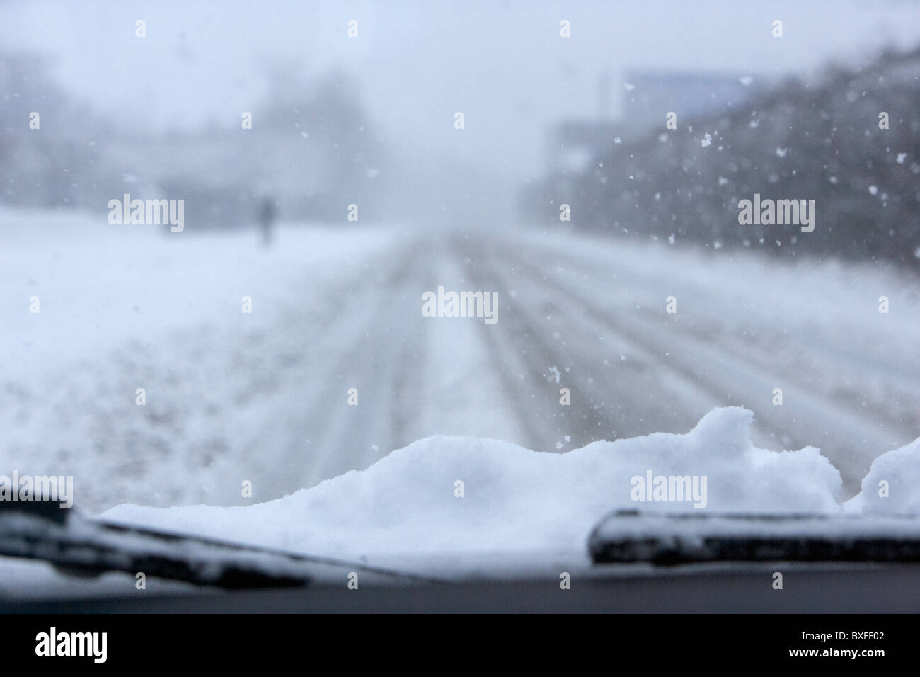 car with snow on the bonnet driving along a cold frozen road on a cold ...
