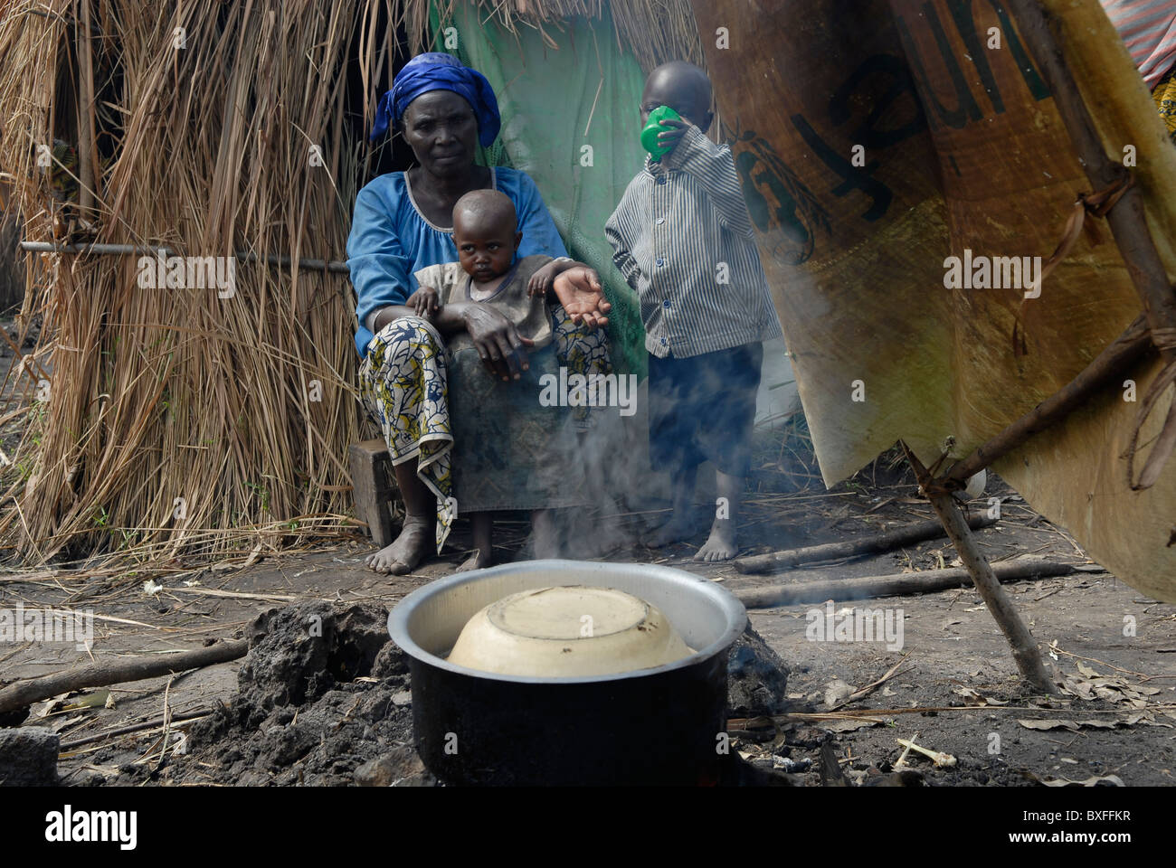 A displaced Congolese woman heats food over bonfire in a makeshift IDP ...