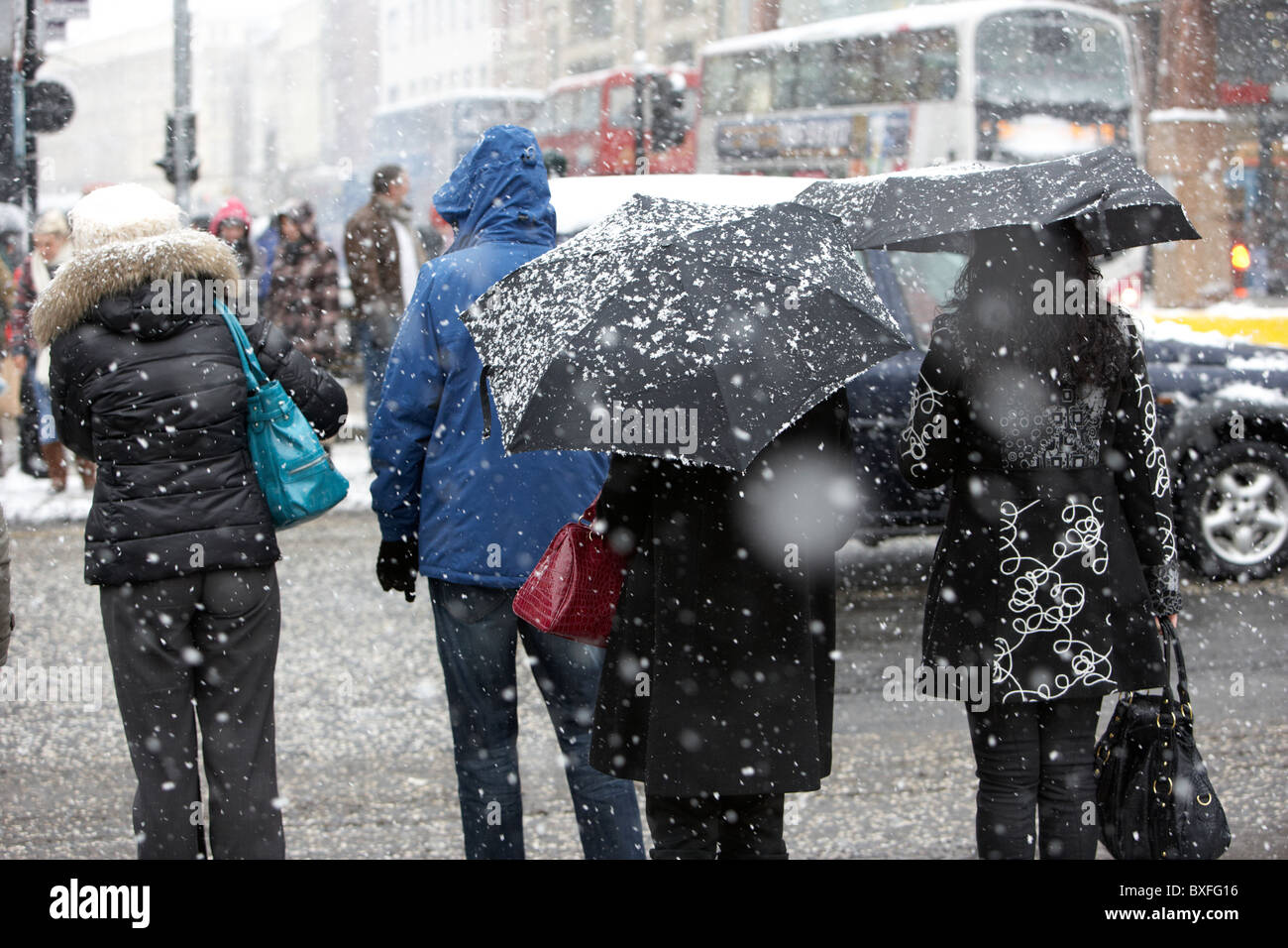 women standing at a pedestrian crossing on a cold snowy winters day ...