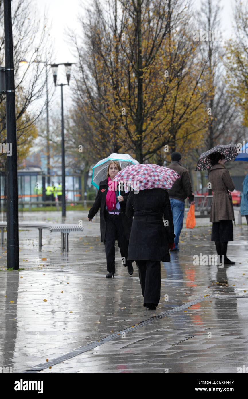 Women office workers walking in the rain on a wet pavement with ...