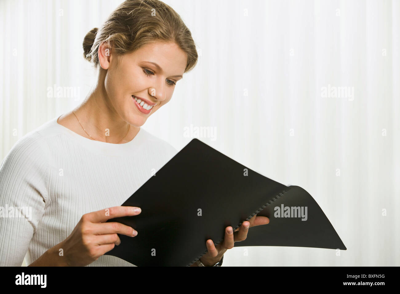 Portrait of beautiful young smiling woman holding the black notebook ...