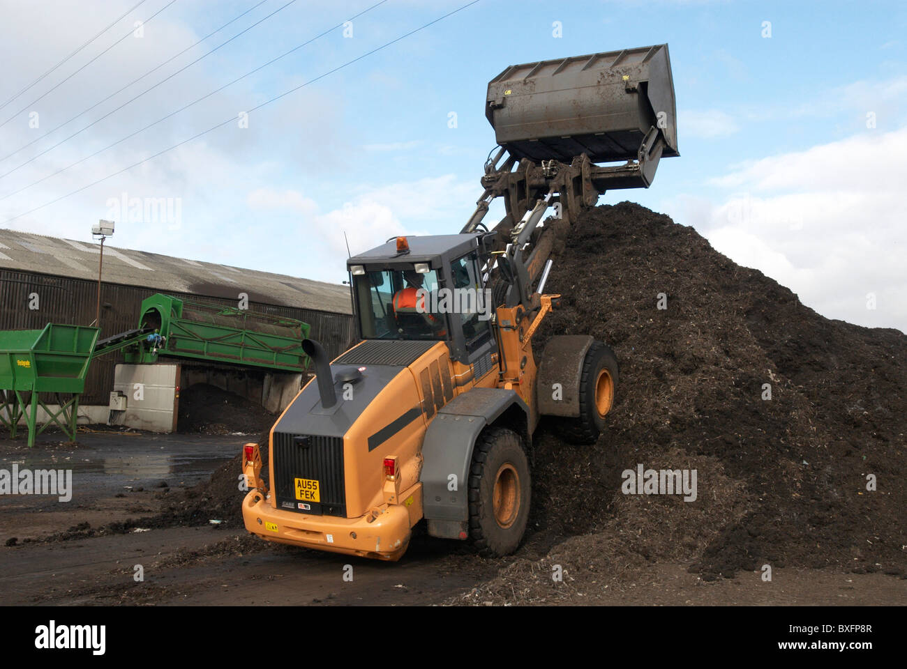 Front loader on compost heap at recycling centre Stock Photo - Alamy