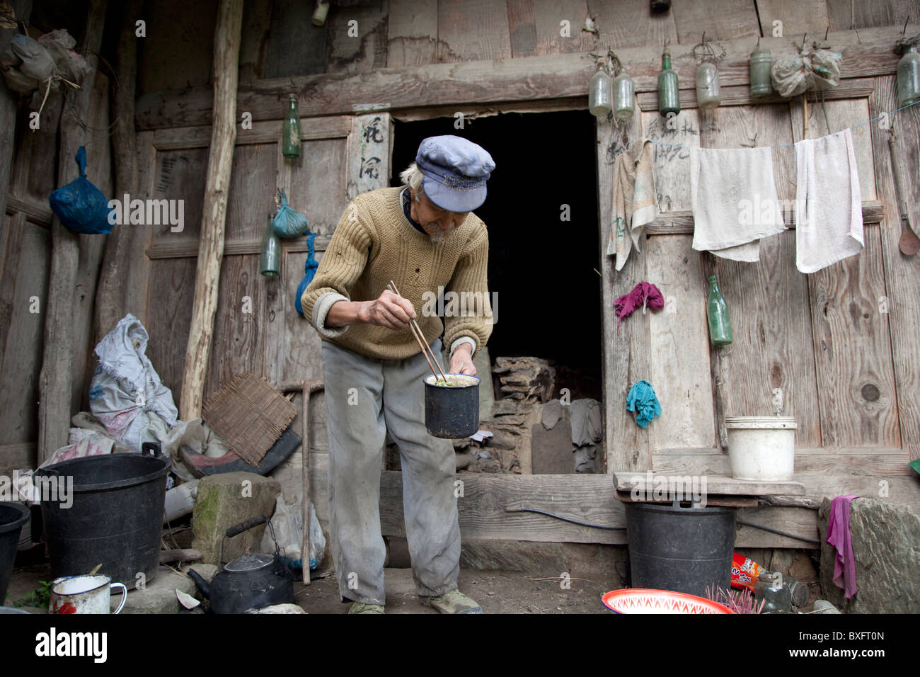 An old man outside his rustic and squalid wooden home in an isolated ...