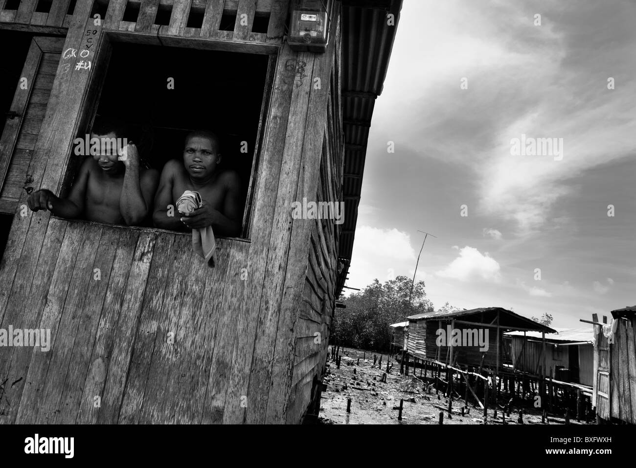 Displaced men look from the window in the stilt house village close to ...