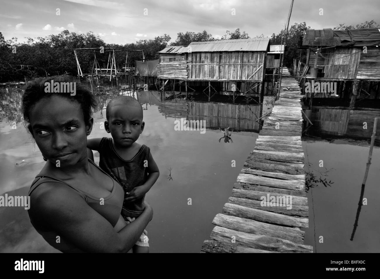 A displaced woman holds her child in the stilt house village close to ...