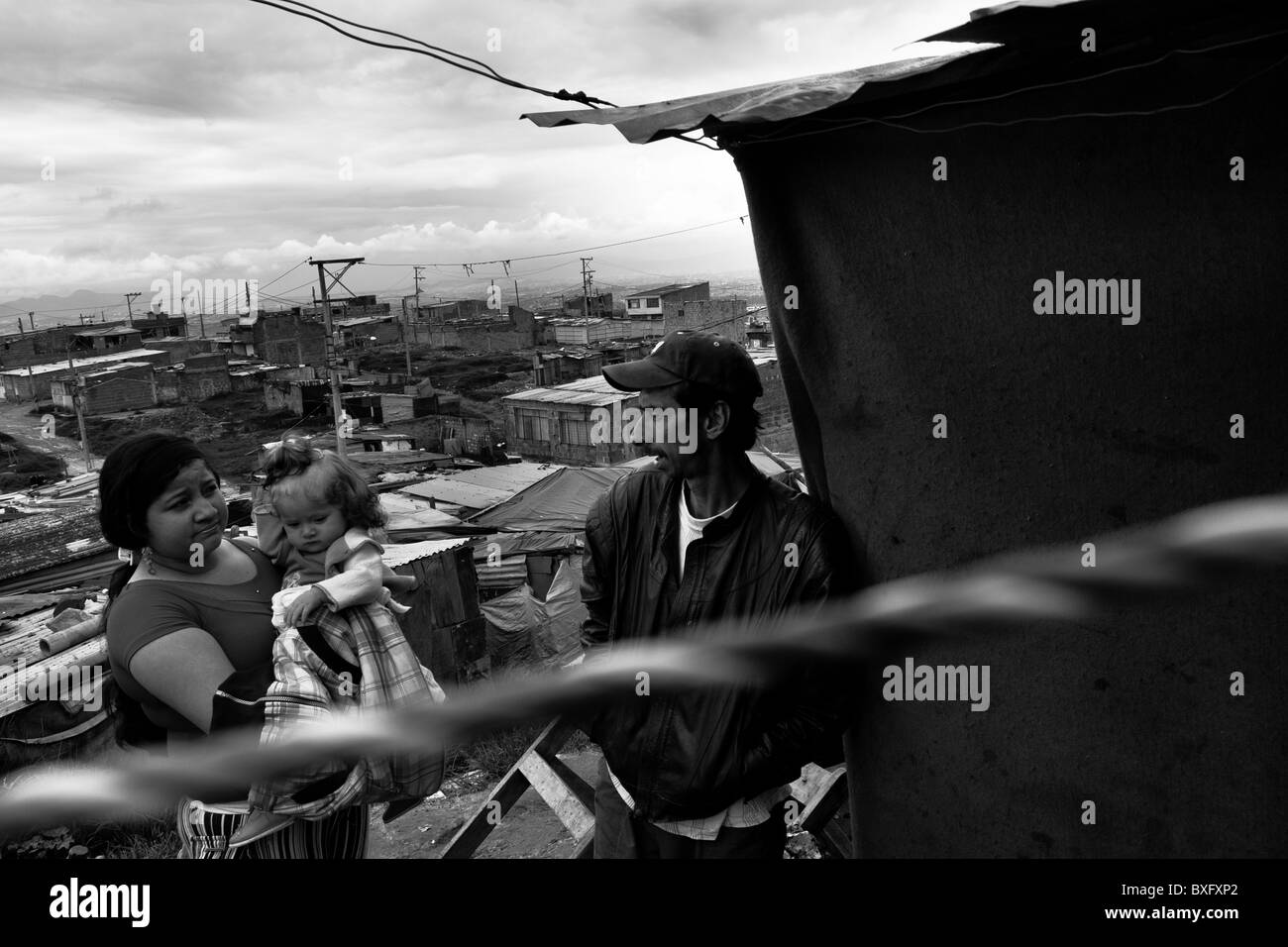 A displaced family from Meta department stands in front of their wooden ...
