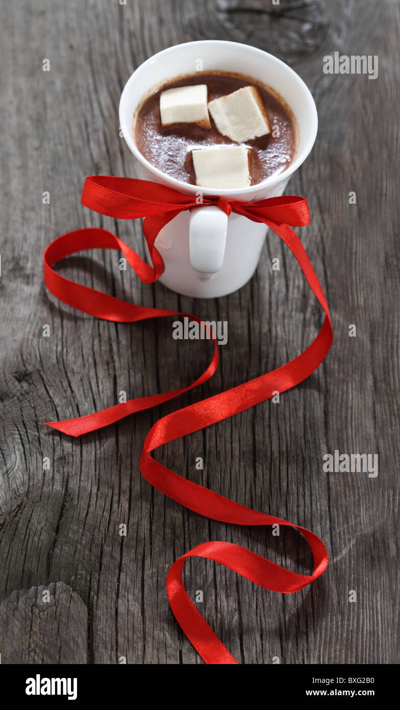 Mug of hot chocolate or cocoa with marshmallows decorated by red ribbon ...