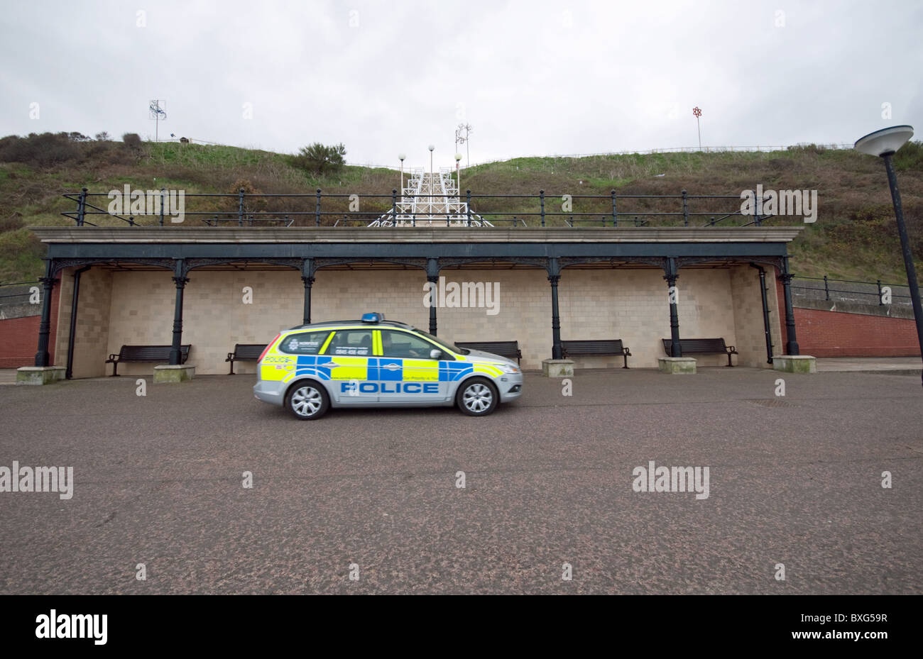 Shelter at Seaside Promenade with seats in car park with passing Police ...