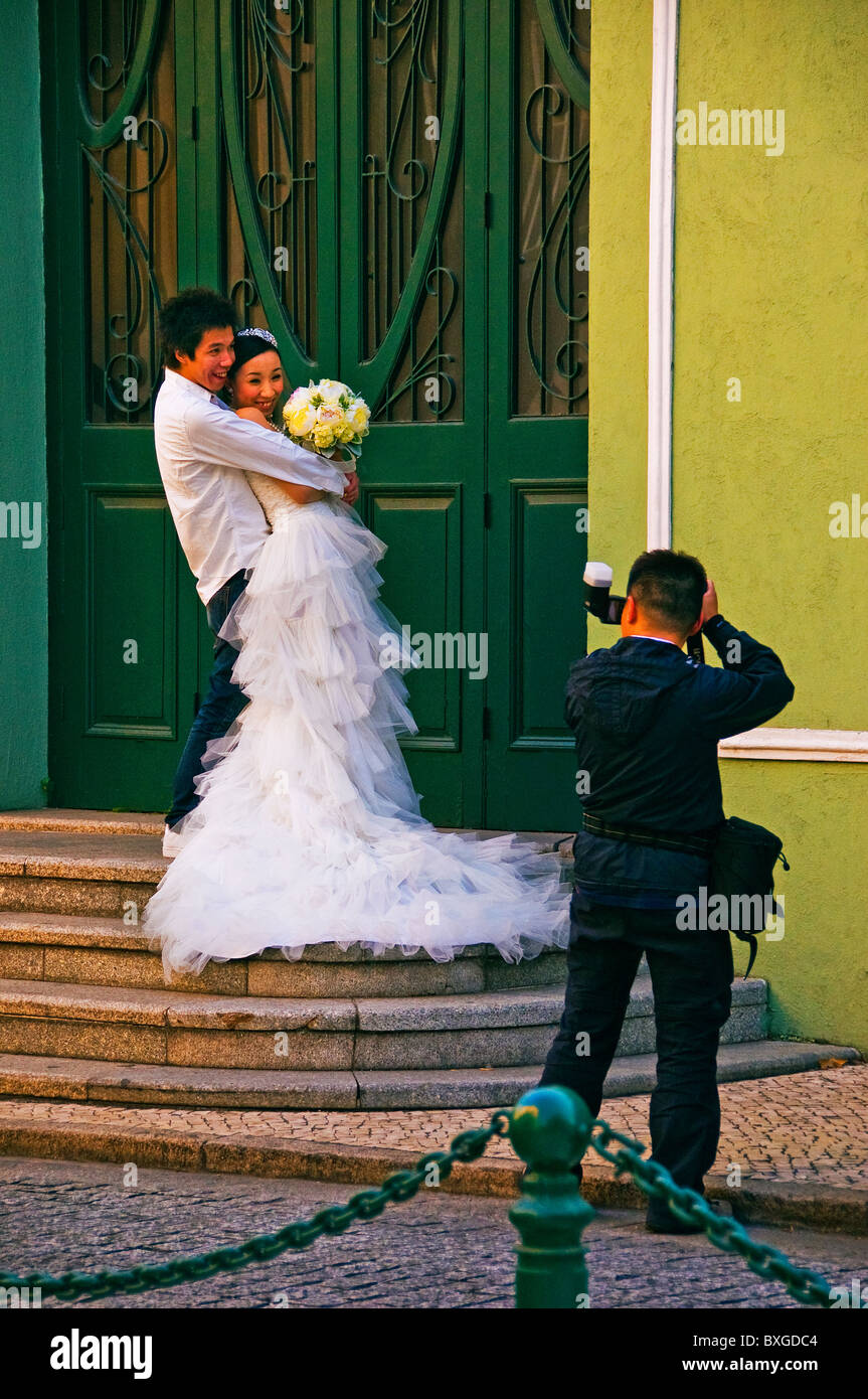 Chinese photographer taking photograph of bride and groom on steps of ...