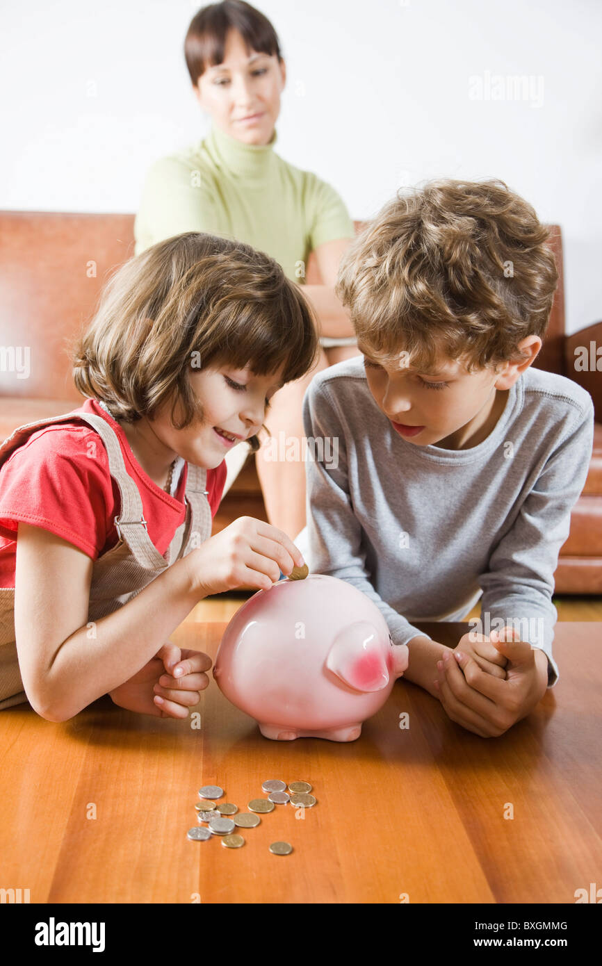 Brother and sister saving money in piggy bank Stock Photo - Alamy