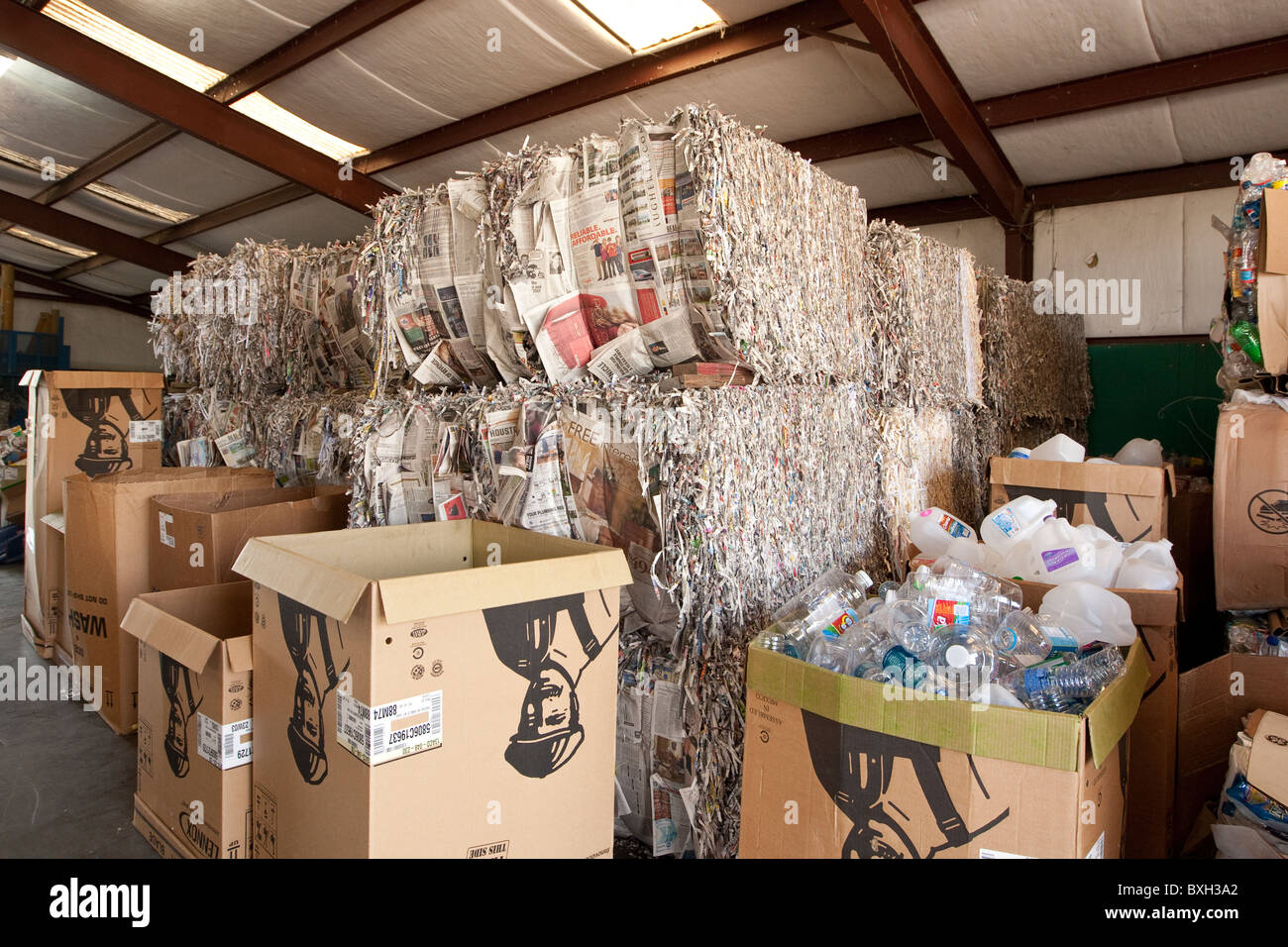 Bales of compacted paper and plastic waste stacked high and boxes of ...