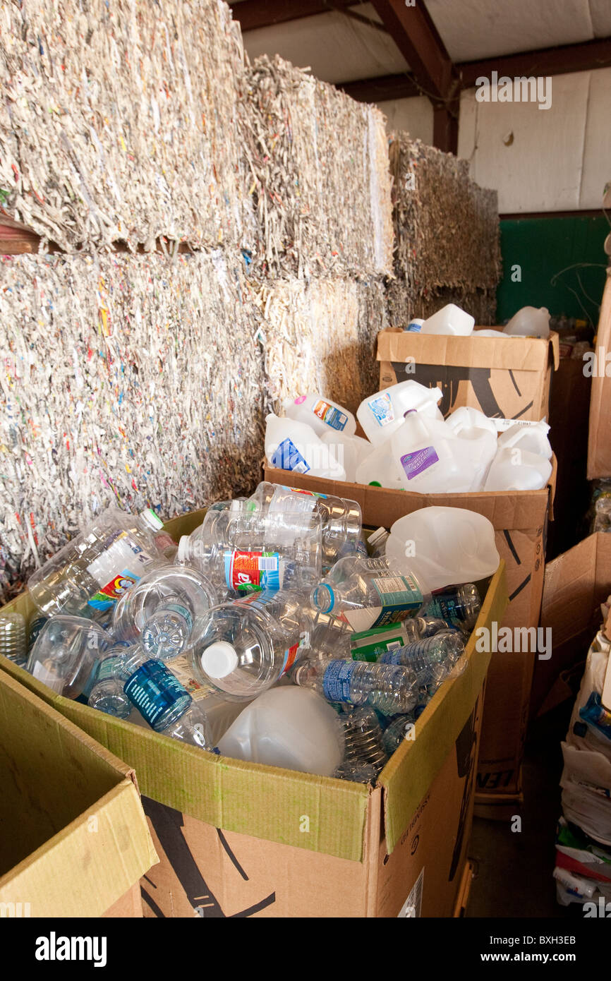 Bales of compacted paper and plastic waste stacked high and boxes of ...