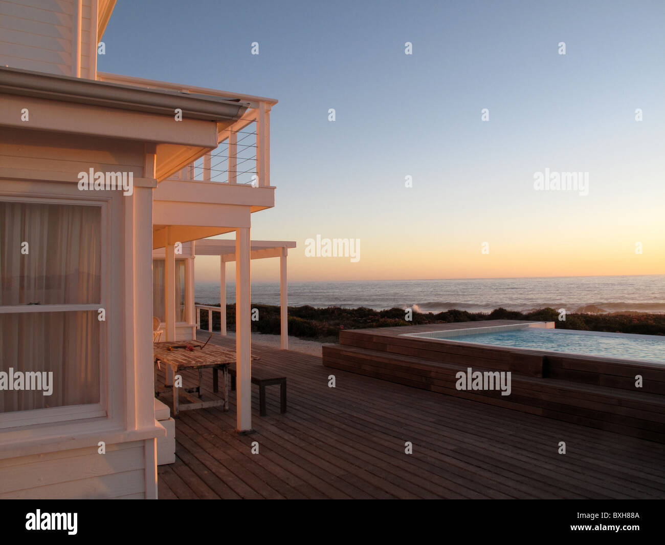 View of the setting sun over the sea from the veranda of a beach front ...