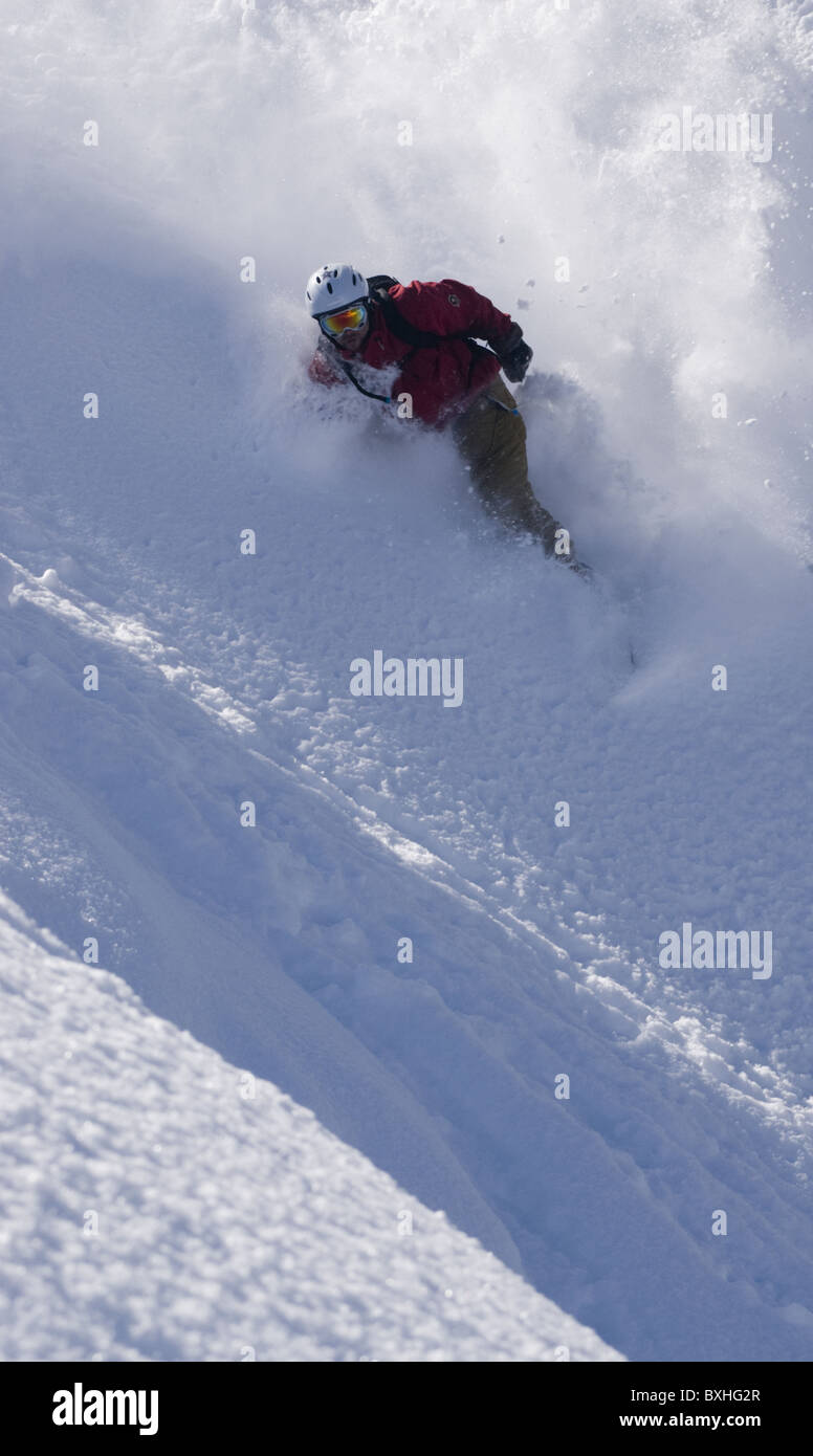 A snowboarder making a turn towards the camera in deep powder snow ...