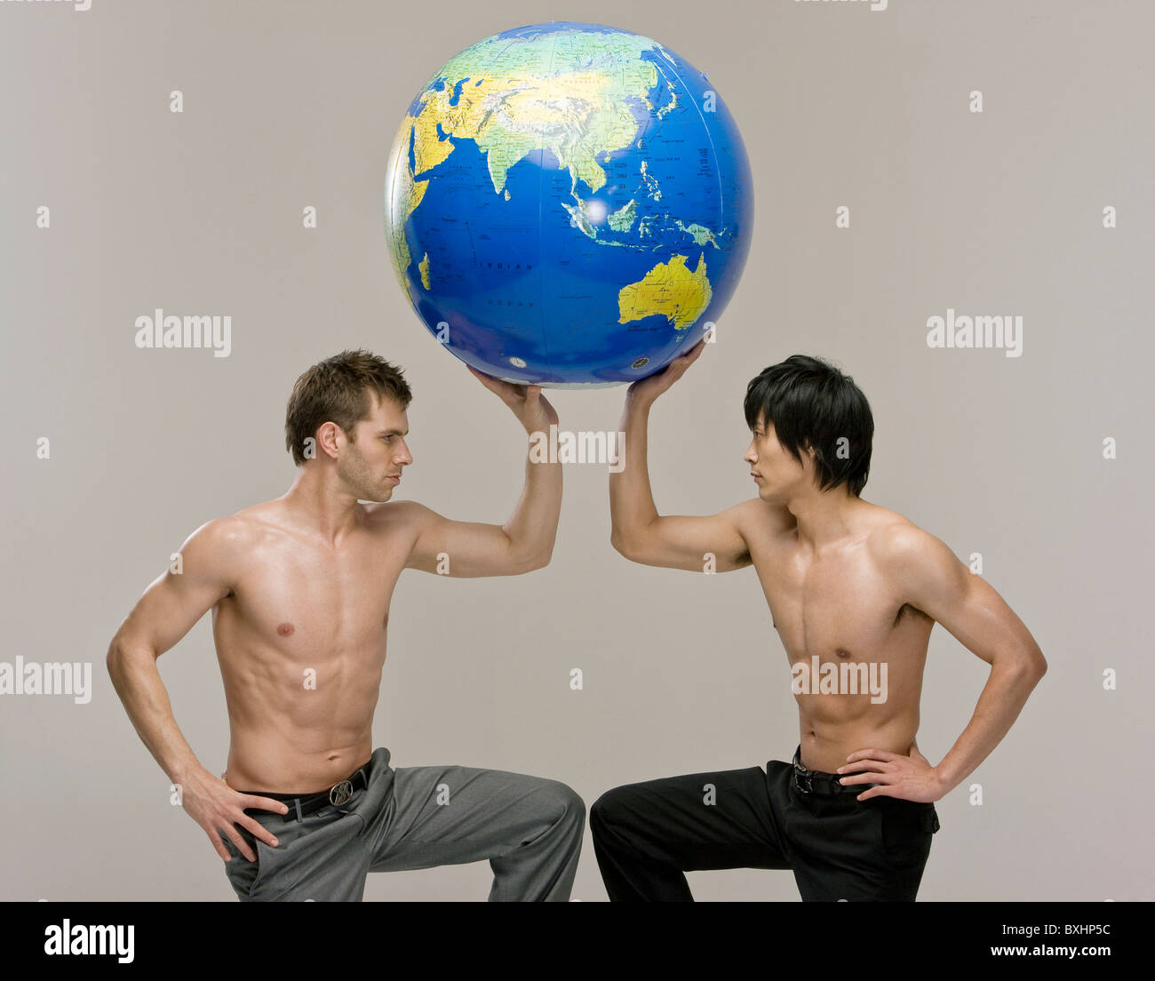 Two young man holding globe together Stock Photo - Alamy
