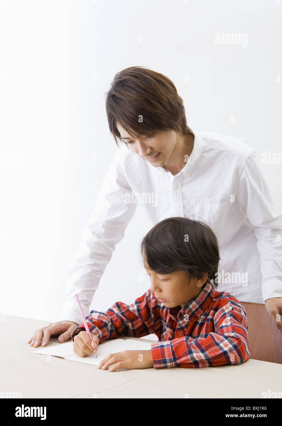 A boy studying with his father Stock Photo - Alamy