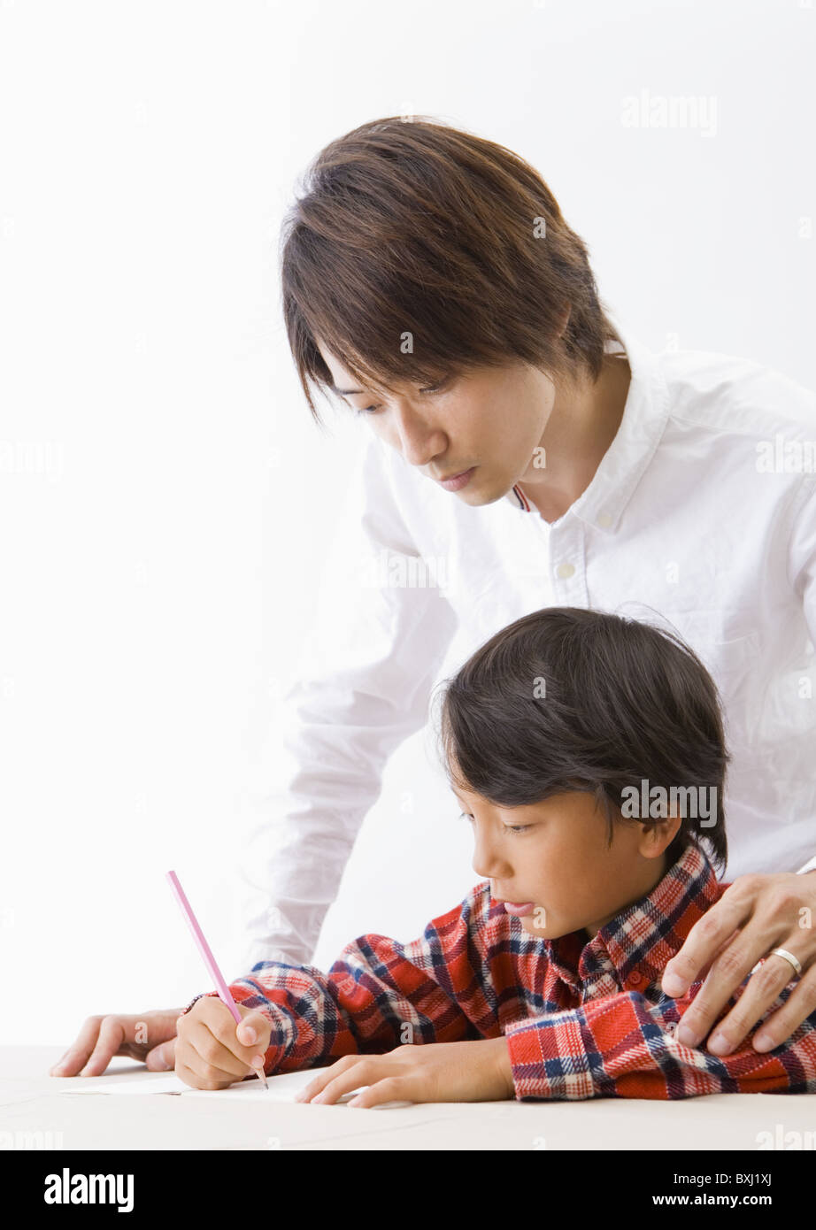 A boy studying with his father Stock Photo - Alamy