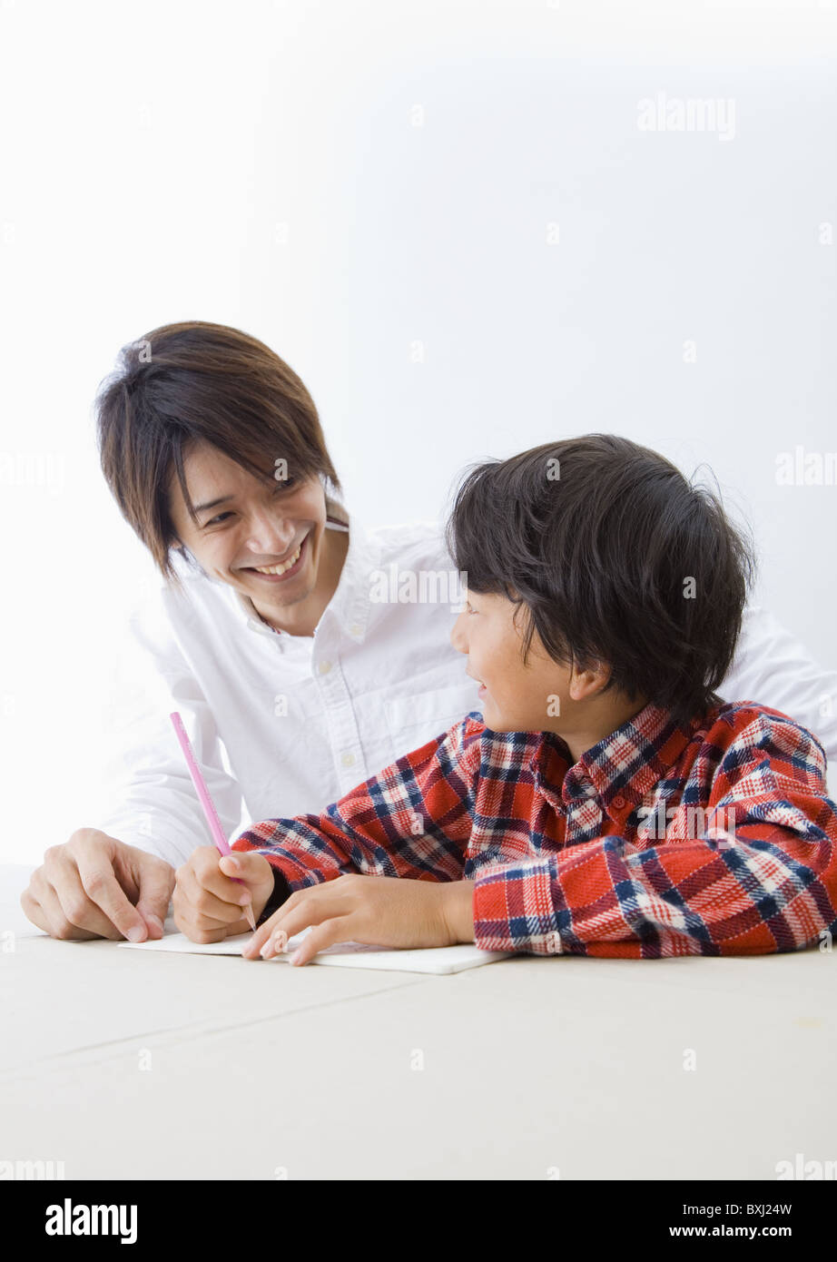 A boy studying with his father Stock Photo - Alamy