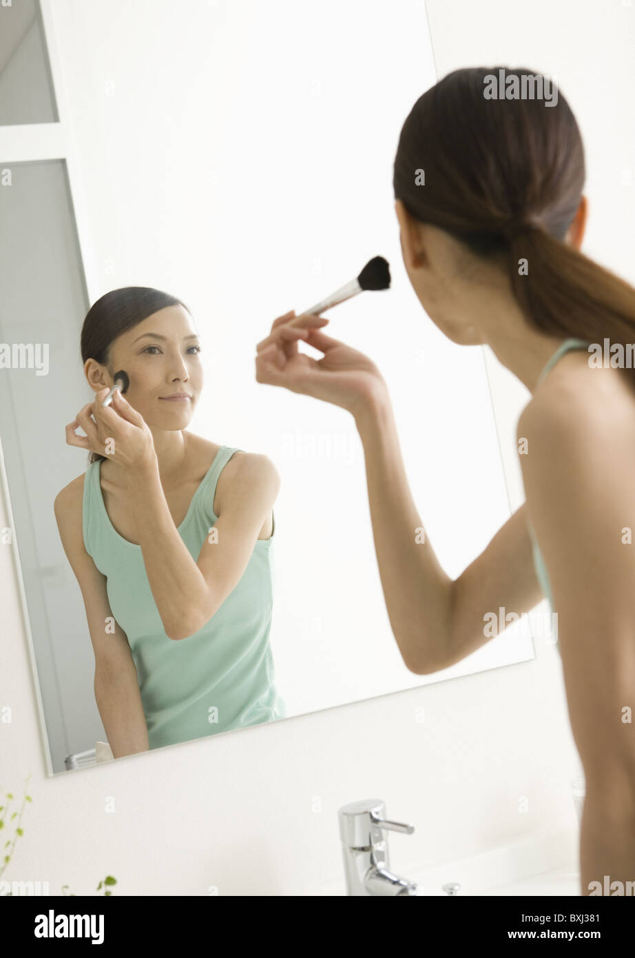 A woman putting on blusher Stock Photo - Alamy