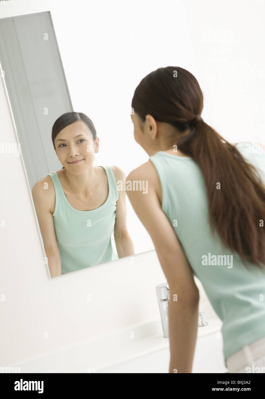 A woman looking in a mirror Stock Photo - Alamy