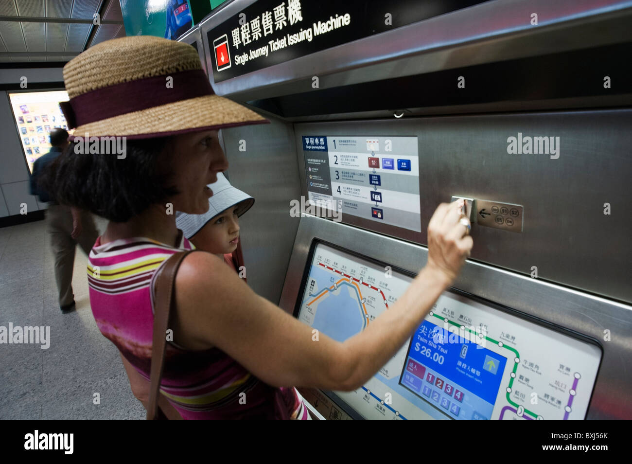 Woman and her son buying a single journey ticket from a ticket issuing ...