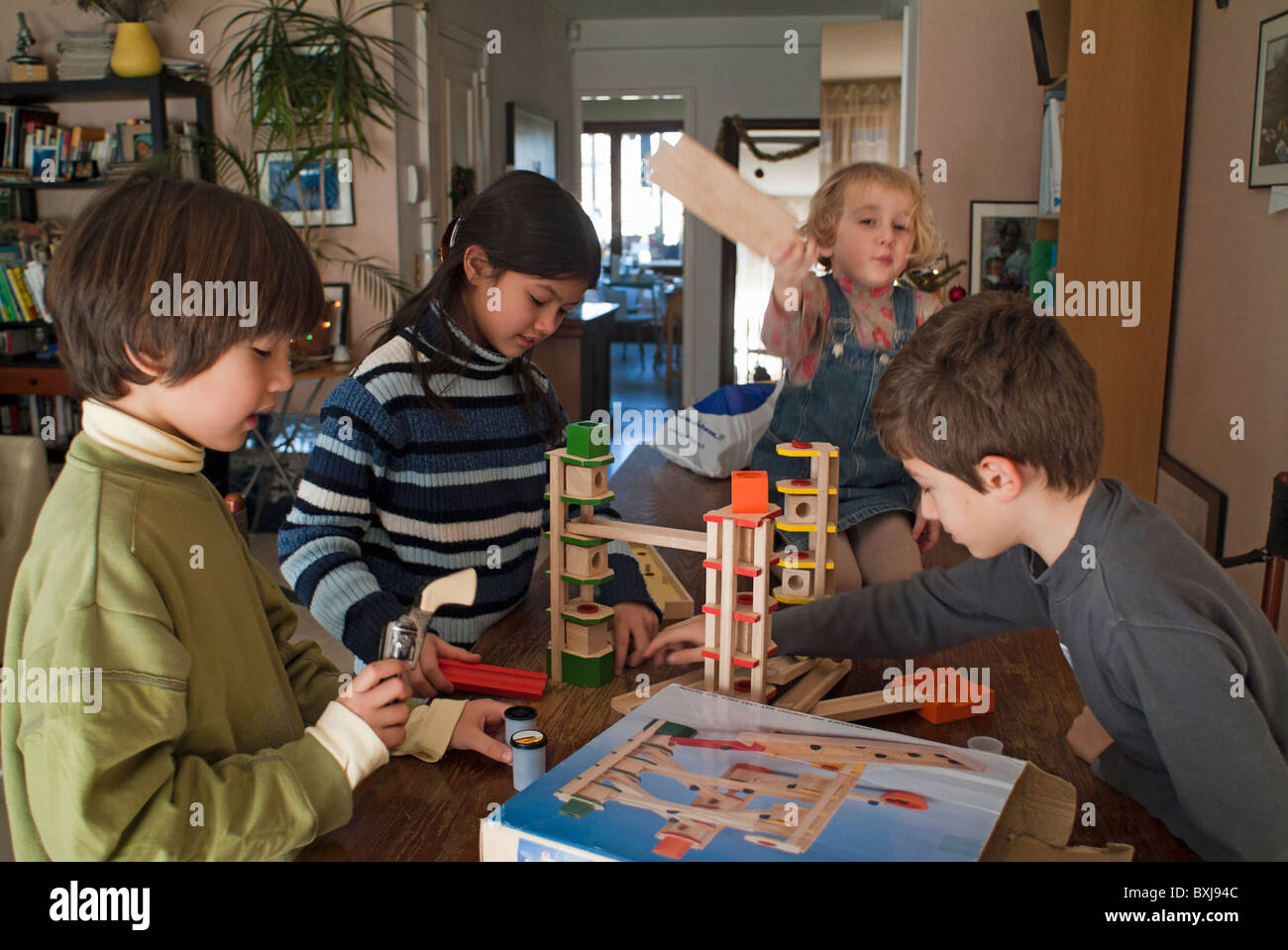 Four children playing together a game on a table in their living room ...