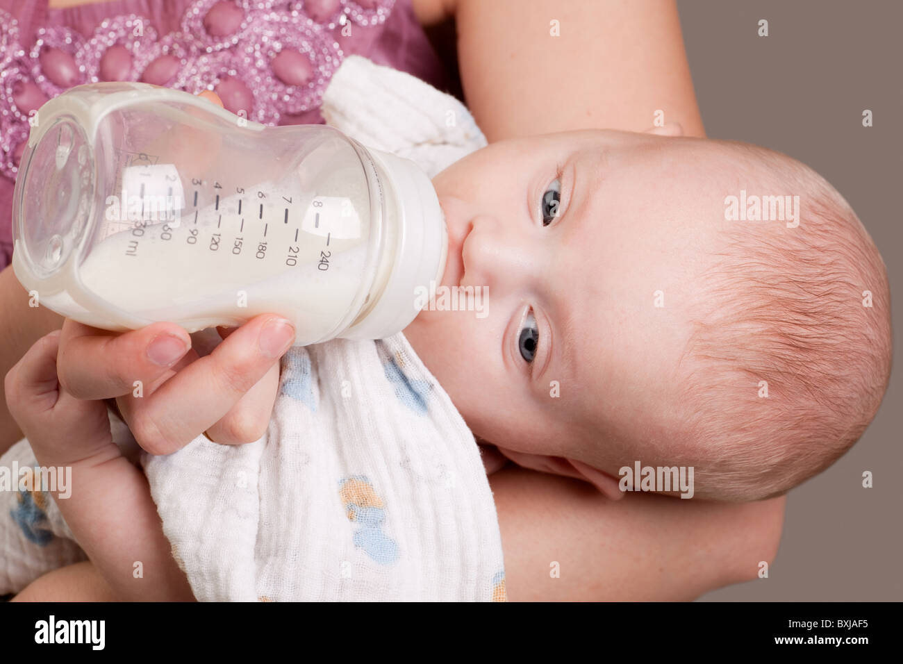 Little hungry baby girl drinking milk from bottle Stock Photo - Alamy