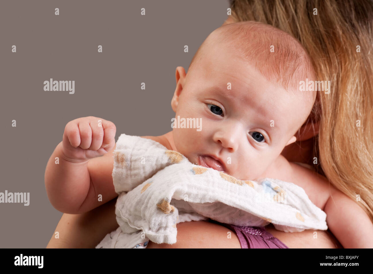 Little cute ten weeks old baby girl on mother's shoulder gesturing ...