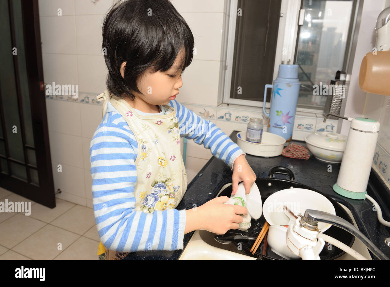 Asian kid washing the dishes in the kitchen Stock Photo - Alamy