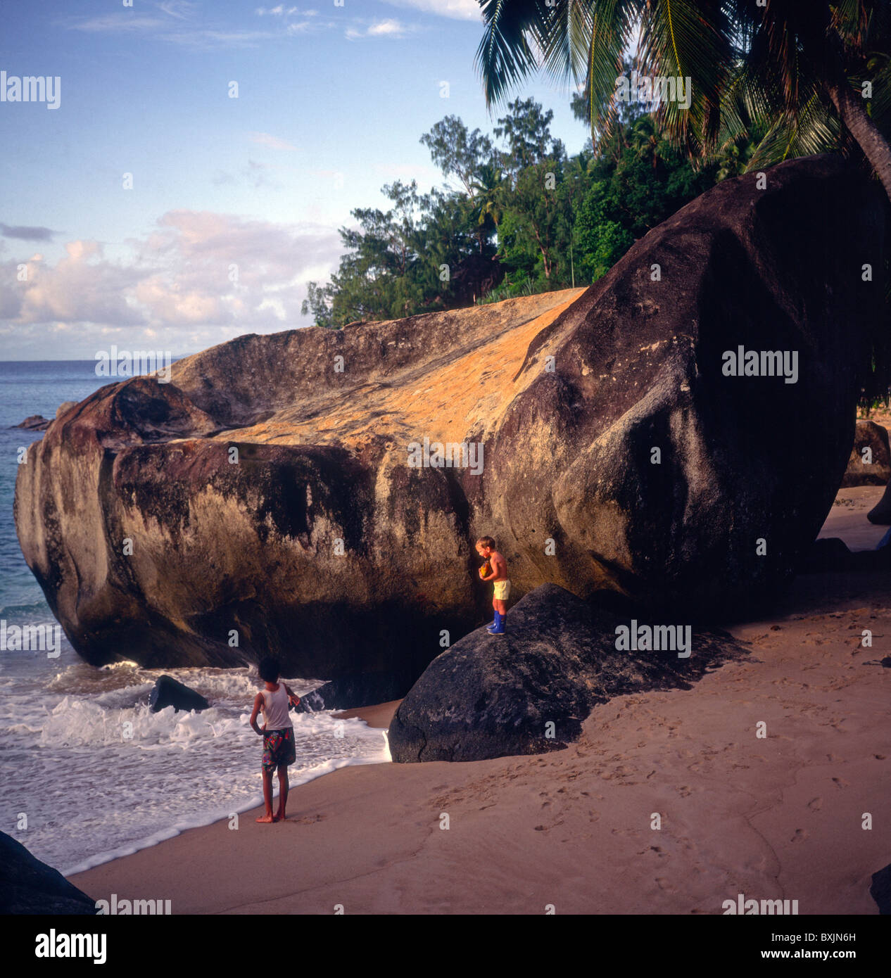 Two boys play beach rocks sea Seychelles Stock Photo - Alamy