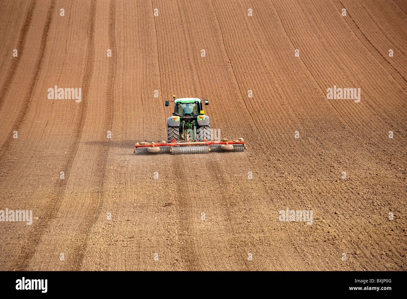 Farmer with soil press rolling seedbed, using John Deere tractor. Kelso ...