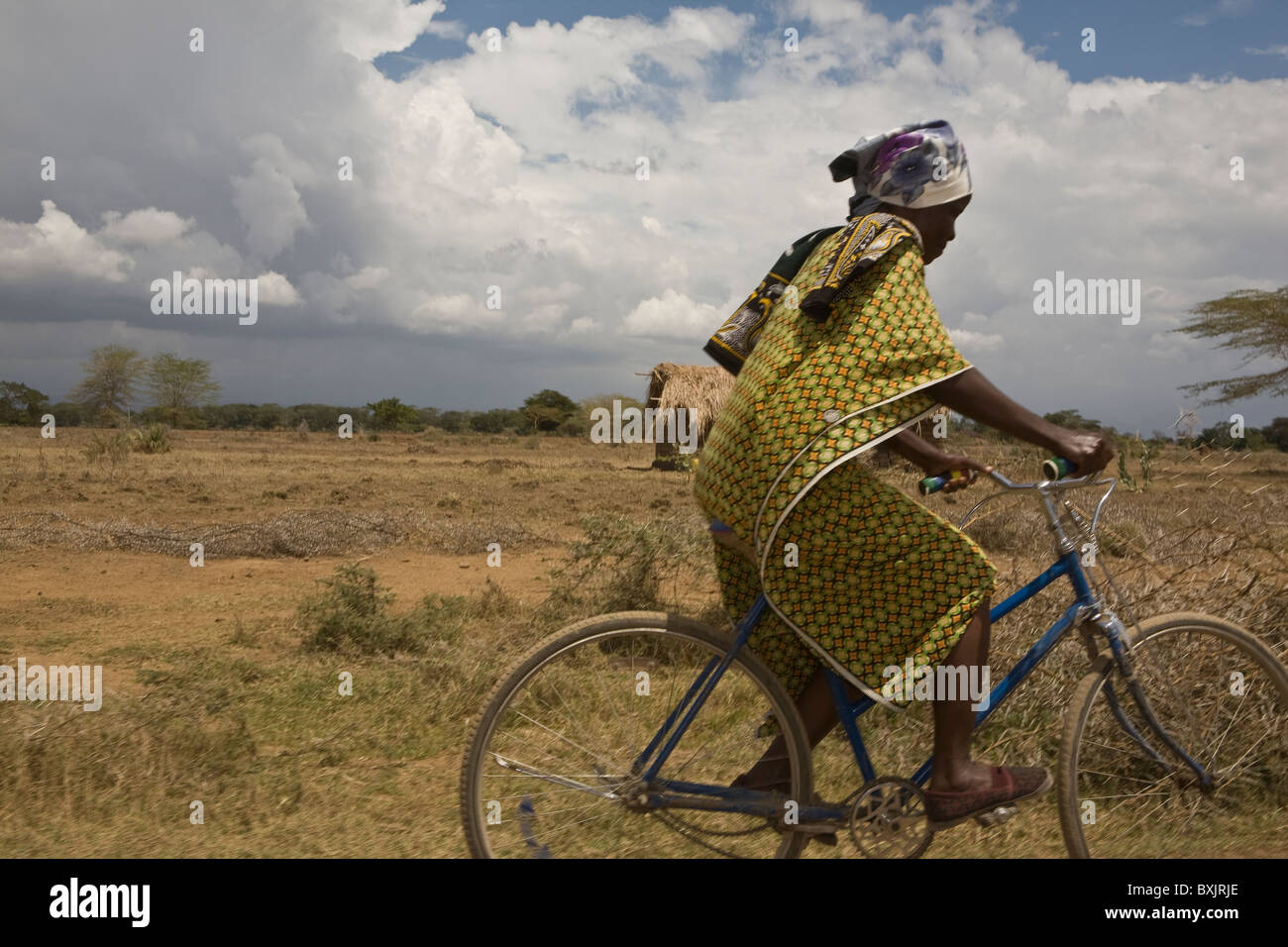 A woman rides a bicycle in a rural village in northern Tanzania, East ...