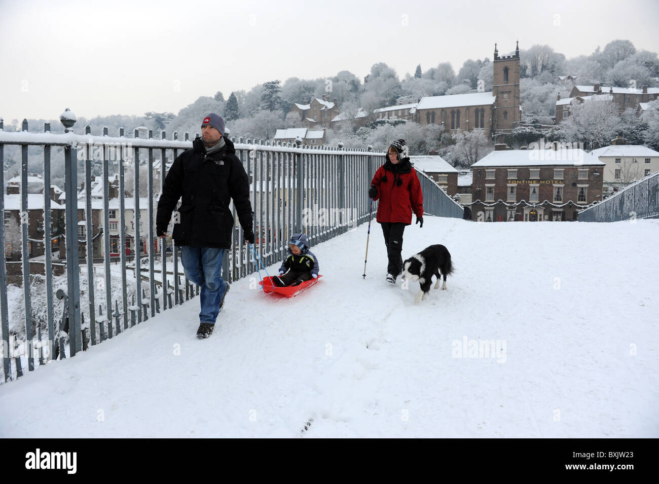 Family walking in the snow with child in a sledge crossing The ...