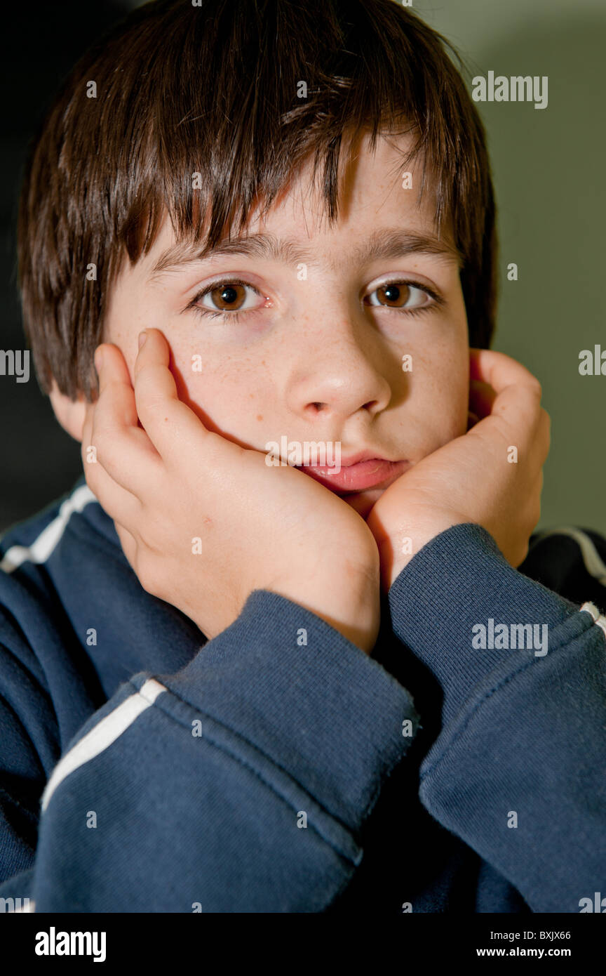 Miserable looking 10 year old boy with his head in his hands looking to ...