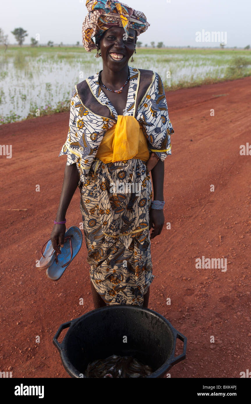 Woman shows her catch of fish from traps in the flooded fields of the ...