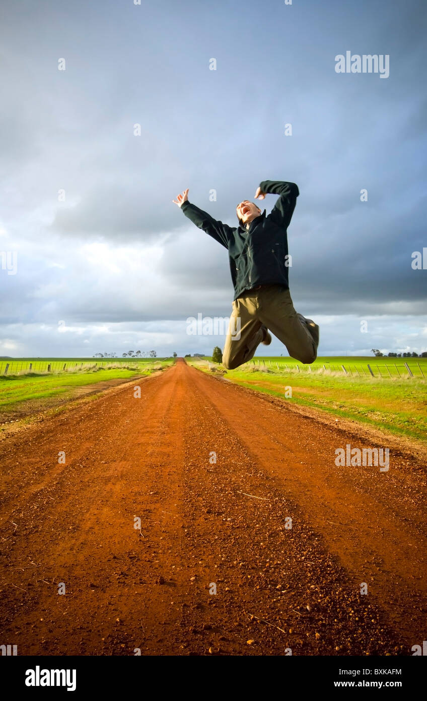 Adult male leaps high into the air with much excitement in a rural area ...