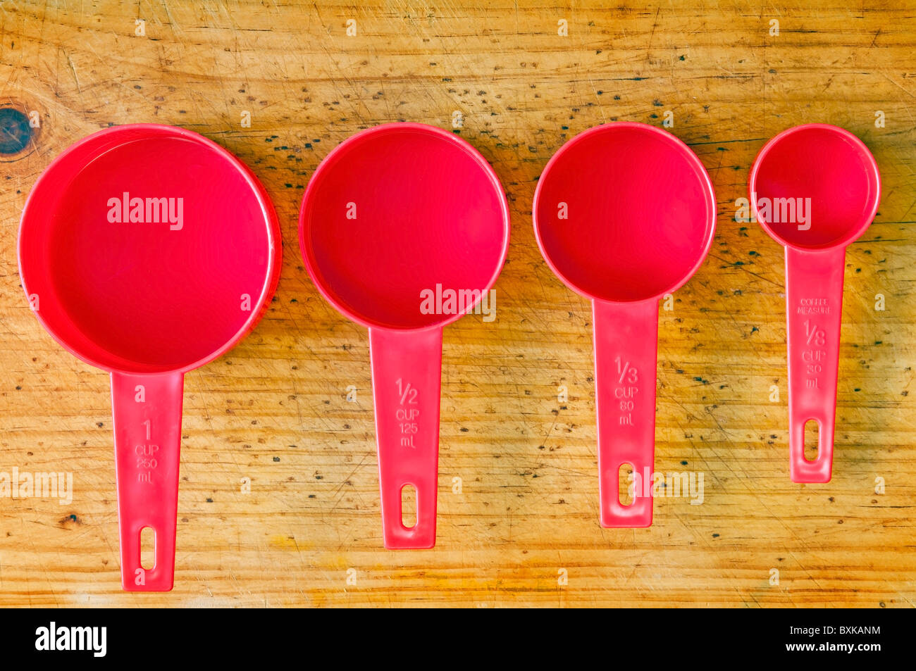 Red measuring cups in different sizes on a timber board Stock Photo - Alamy