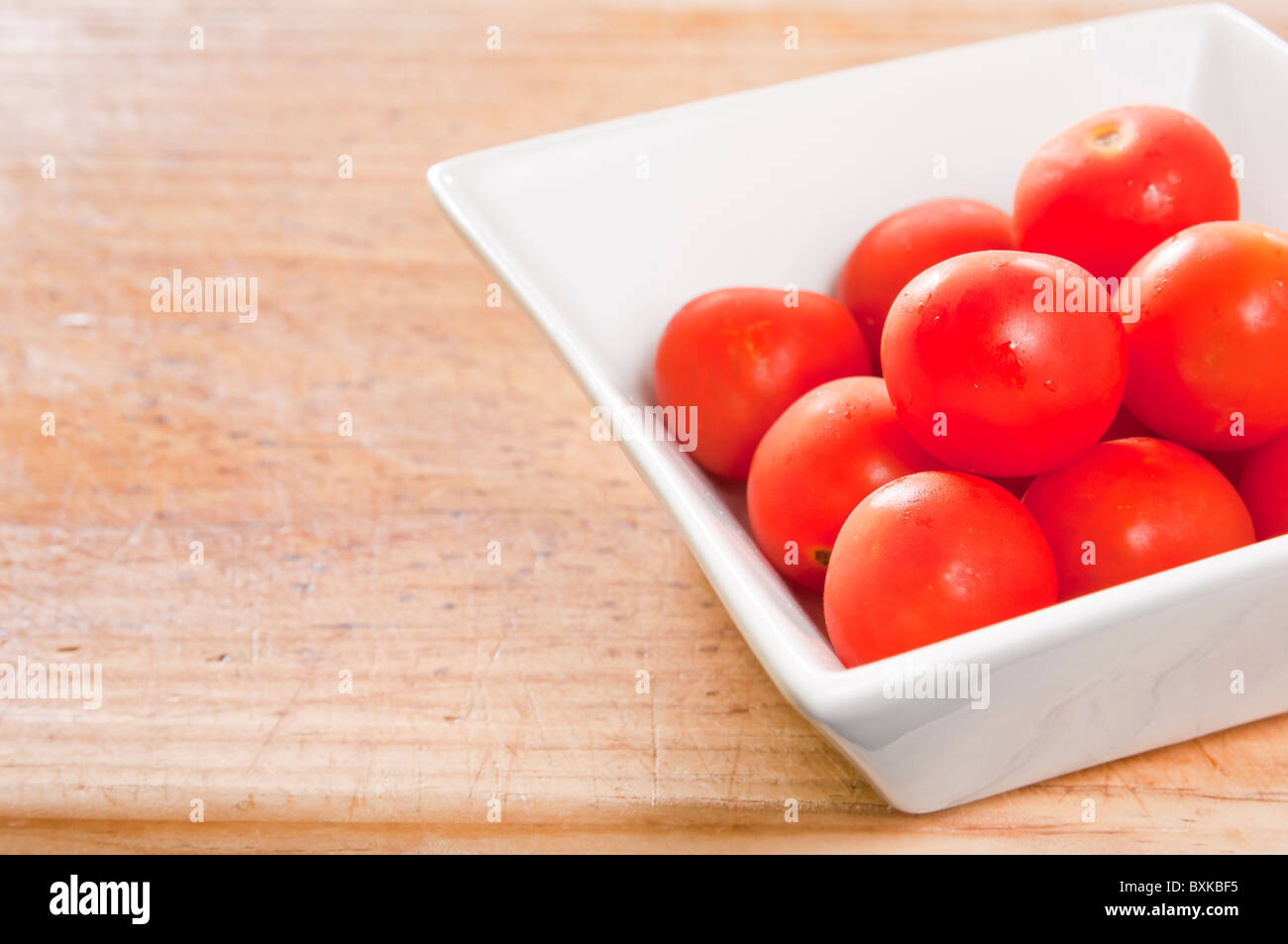 Small red tomatoes sit in a modern white bowl on timber Stock Photo - Alamy