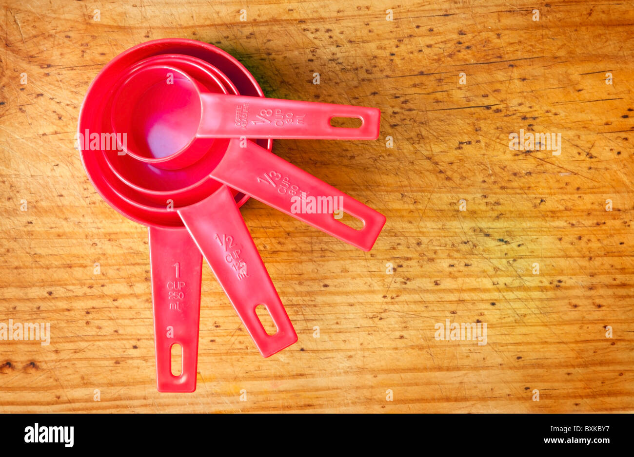 Red measuring cups in different sizes on a timber board Stock Photo - Alamy