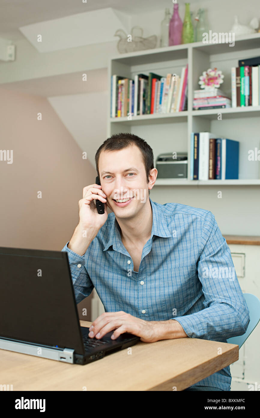 Young man using laptop and phone Stock Photo - Alamy