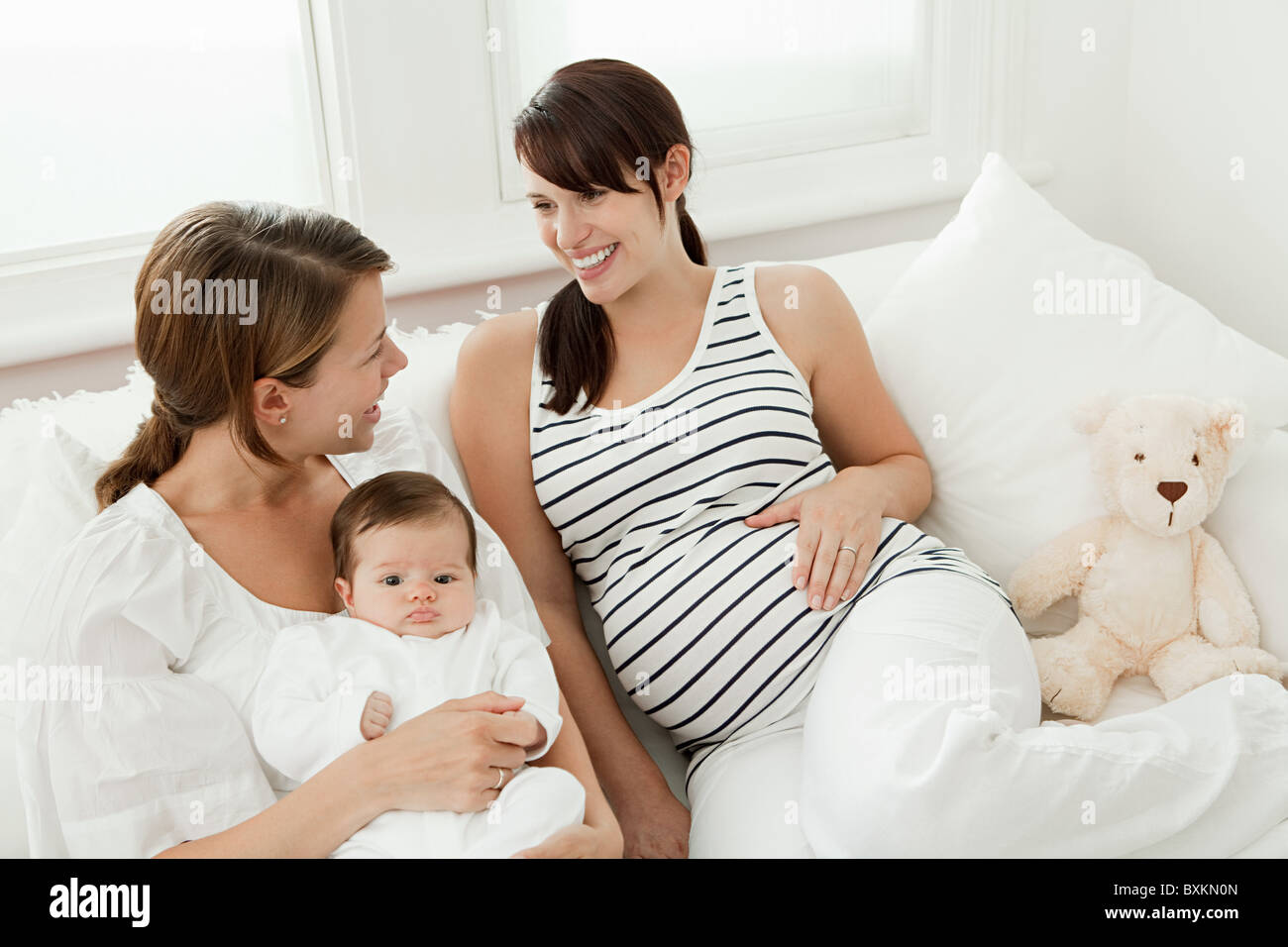 Mother with baby girl and pregnant friend Stock Photo - Alamy
