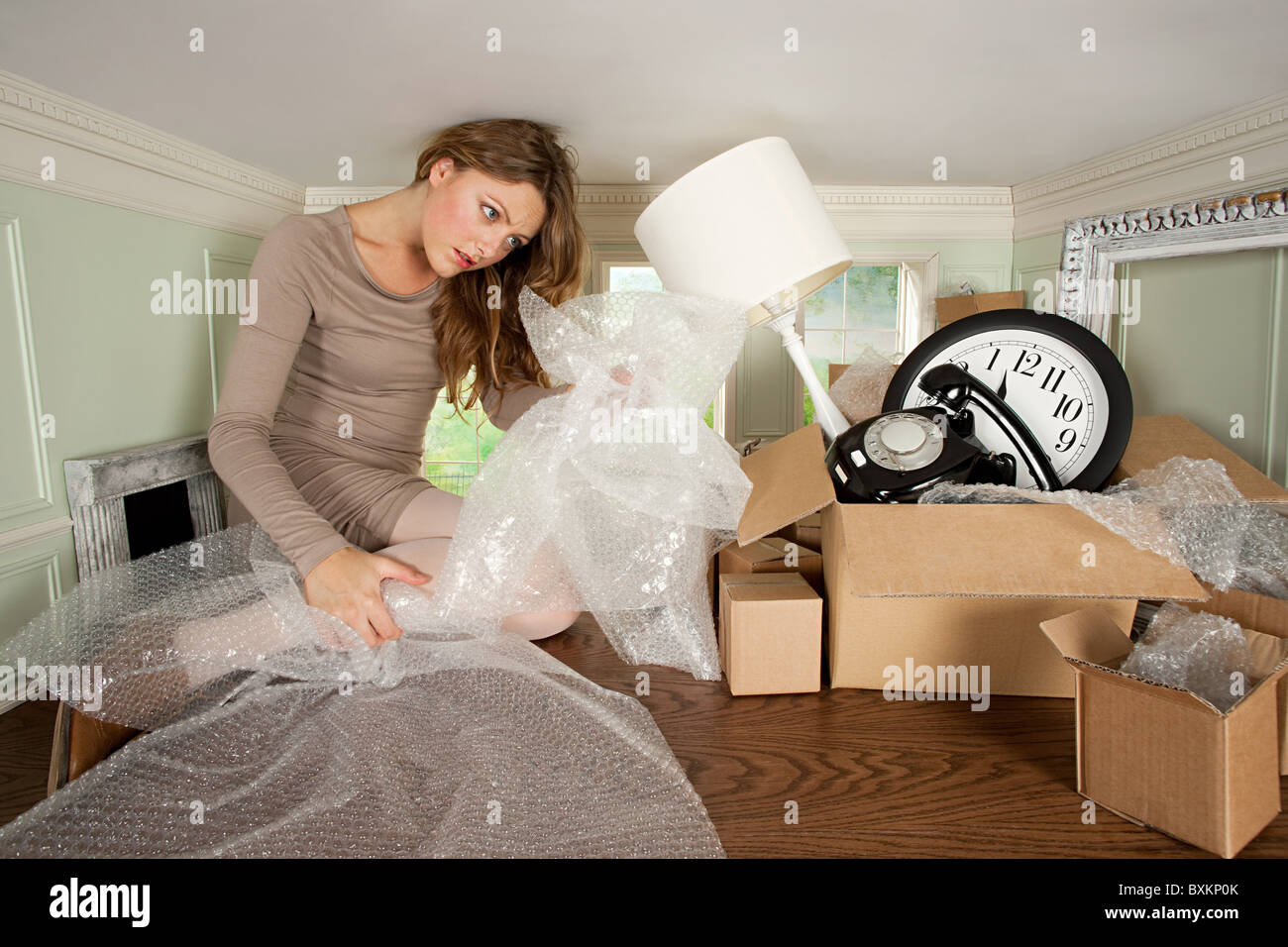 Young woman packing box of objects in small room Stock Photo - Alamy