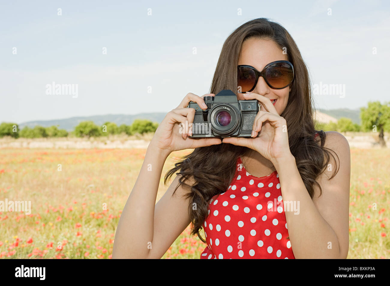 Young woman with camera in poppy field Stock Photo - Alamy